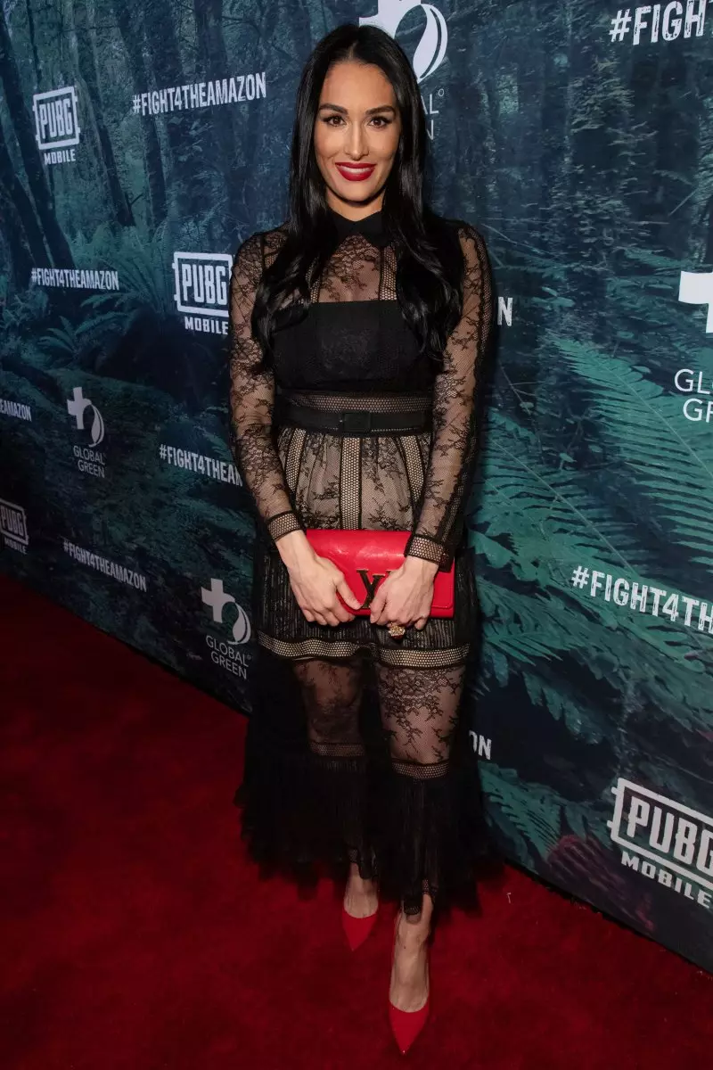 Nikki Bella leva un vestido de encaixe negro transparente e un clutch vermello