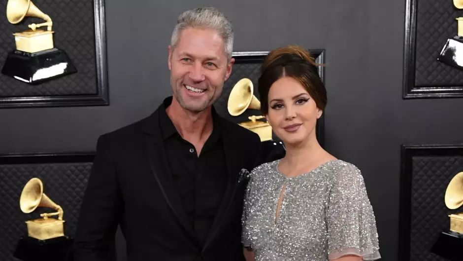 Lana Del Rey สวมชุดเดรสแขนสั้นสีเงินและ Updo กับอดีตแฟนหนุ่ม Sean Larkin ในชุดสูทสีดำที่ Grammys