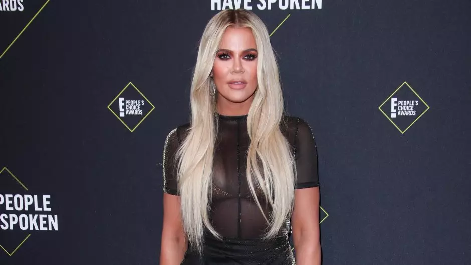 Khlow Kardashian ma na sobie czarny przezroczysty top i spódnicę z wysokim rozcięciem z długimi blond włosami