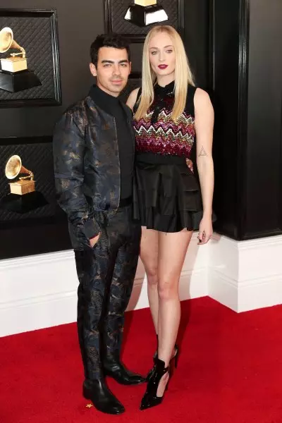 D'Sophie Turner huet e kuerze Ruffled Rock a Regenbogenstreift Top um rouden Teppech mam Mann Joe Jonas am schwaarze Kostüm