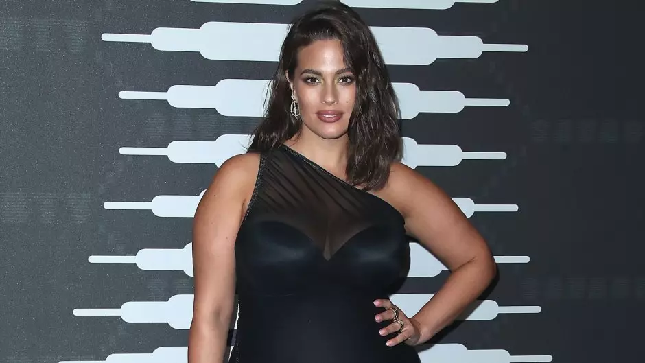 Ashley Graham yang sedang hamil berpose dalam gaun hitam