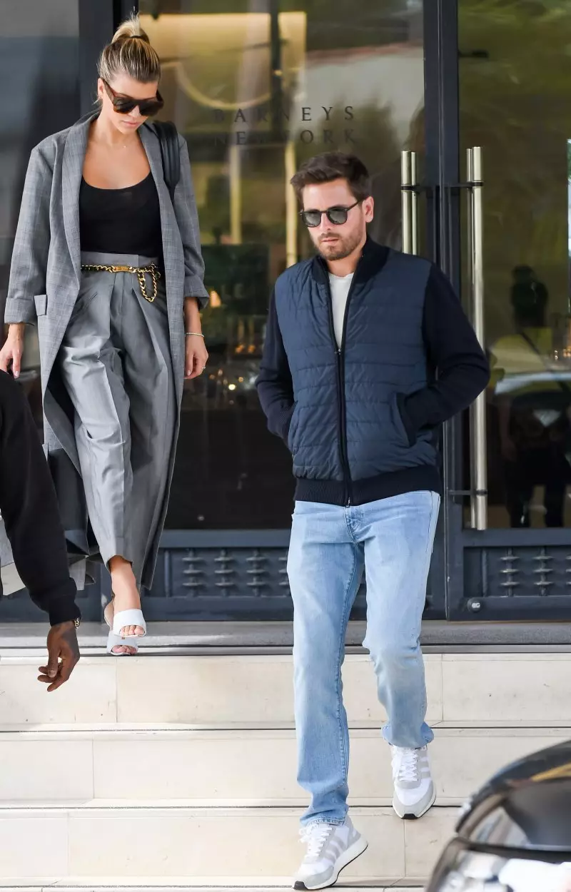 Sofia Richie suti yabuluu yotuwa m'chiuno chapamwamba thalauza lamba wagolide thanki yakuda pamwamba pa ponytail zomangira za Scott Disick jekete yabuluu imvi tshirt magalasi a buluu a jeans