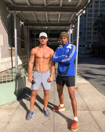 Tyler Cameron ohne Hemd steht mit Mitbewohner Matt James in Jacke und Shorts