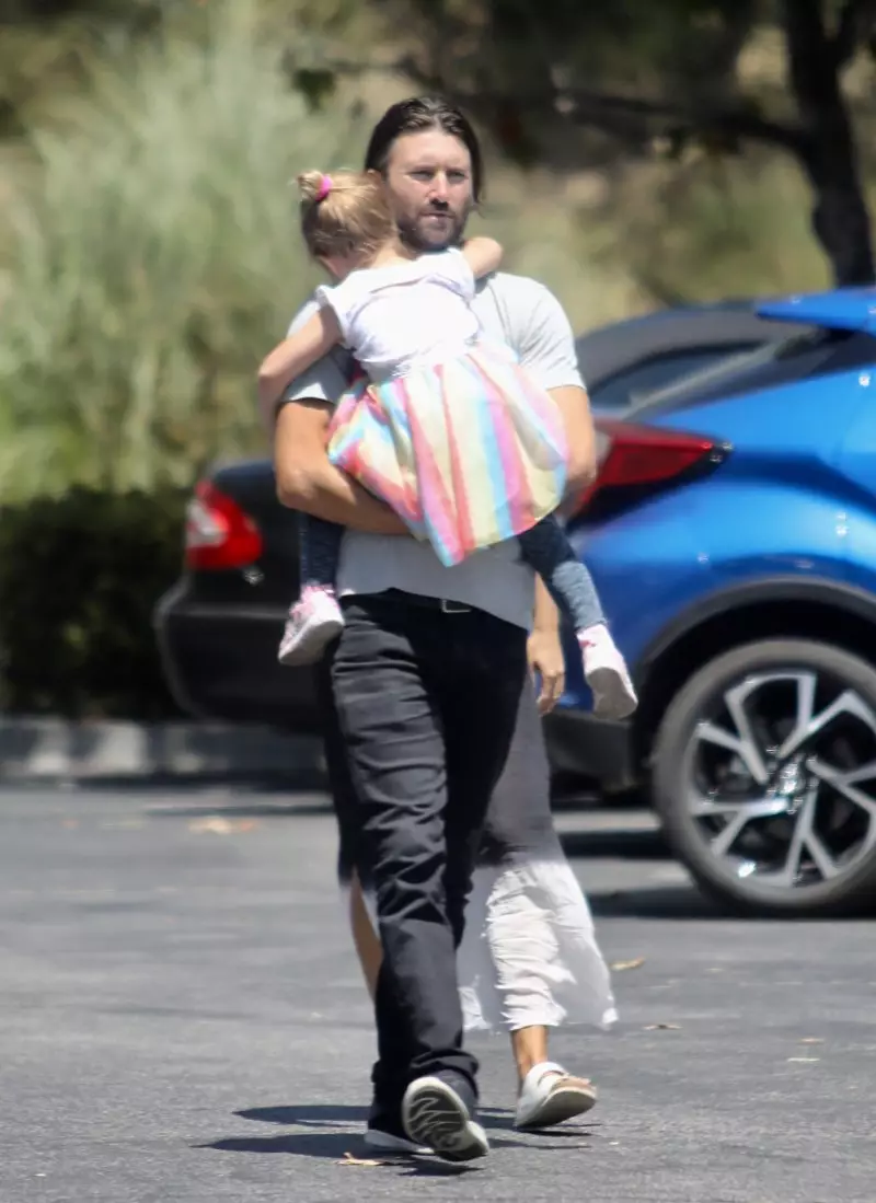 Brandon Jenner jade ni ṣiṣe awọn errands bulu seeti ati sokoto dani ọmọbinrin Eva nigba ti nṣiṣẹ errands