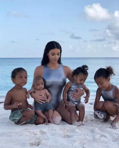 Kim Kardashian og hennes fire barn på stranden iført matchende sølv badedrakter