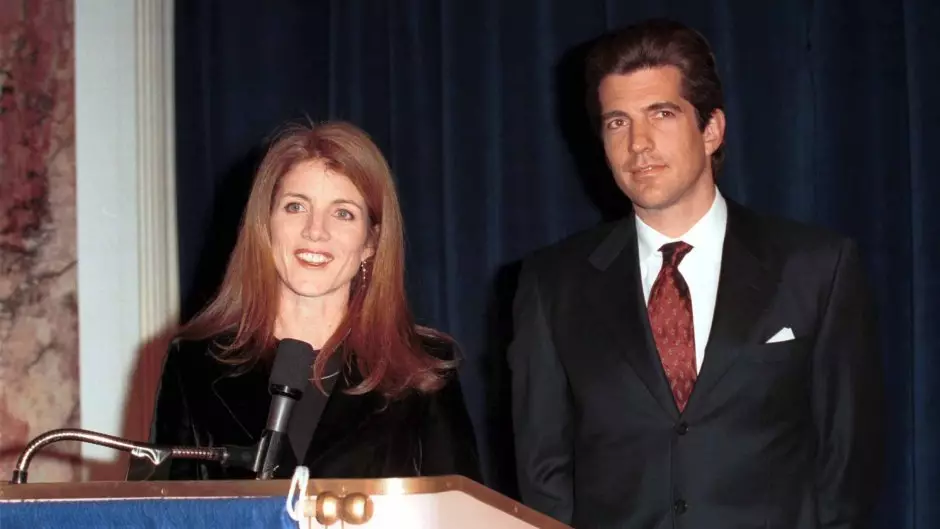 John F. Kennedy dhe CAROLINE KENNEDY duke qëndruar dhe duke buzëqeshur pas podiumit