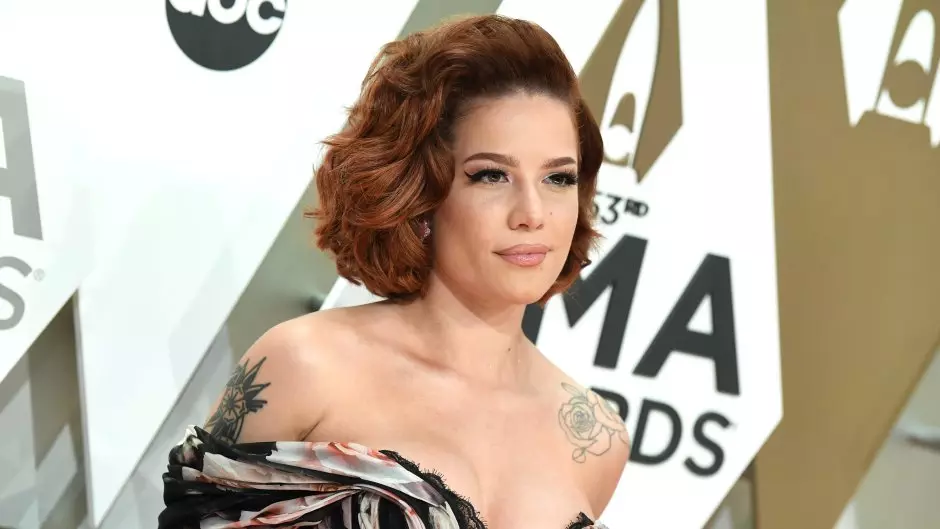 Halsey lächelt in einem schulterfreien Kleid und kurzen roten Haaren