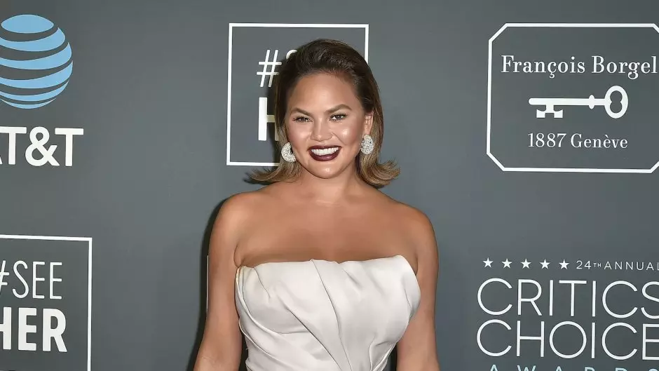 Chrissy Teigen nganggo busana satin putih ing Critics' Choice Awards