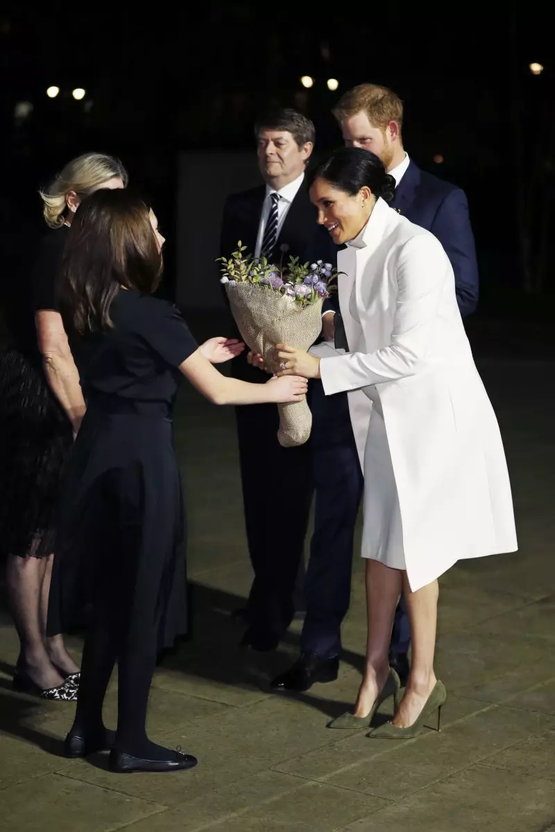 Meghan Markle in abito bianco con il principe Harry in abito blu navy