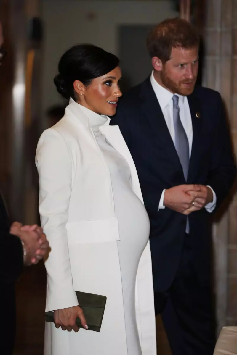 Meghan Markle in abito bianco con il principe Harry in abito blu navy