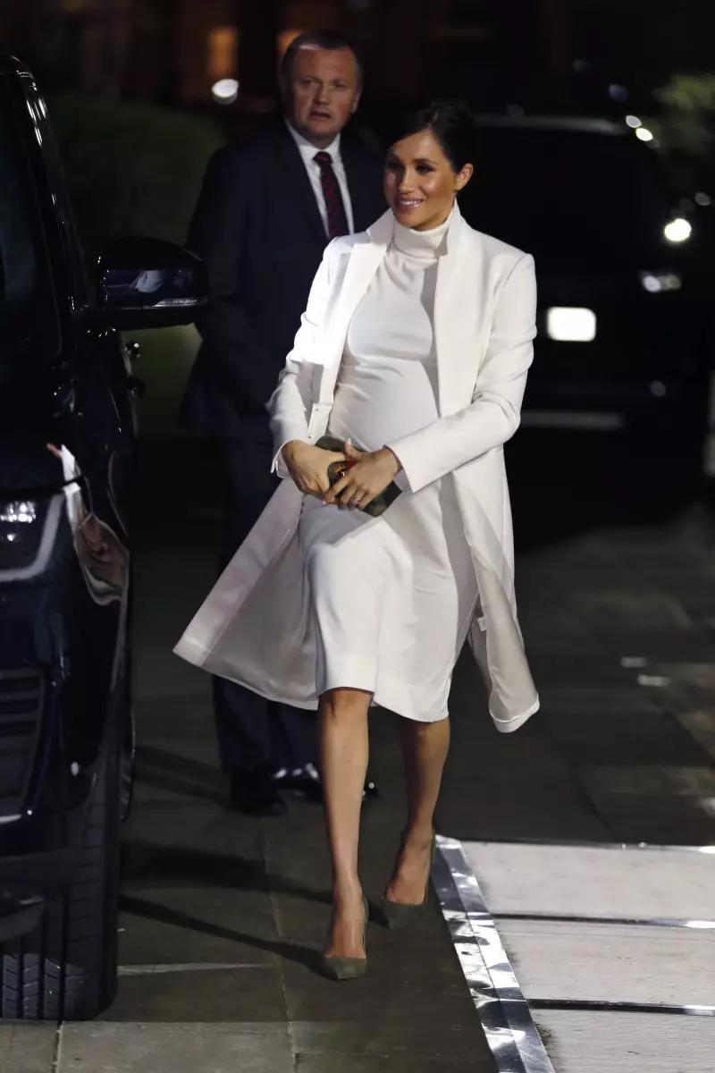 Meghan Markle in abito bianco con il principe Harry in abito blu navy