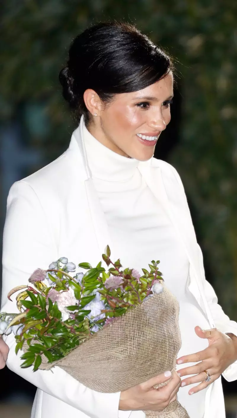 Meghan Markle in abito bianco con il principe Harry in abito blu navy