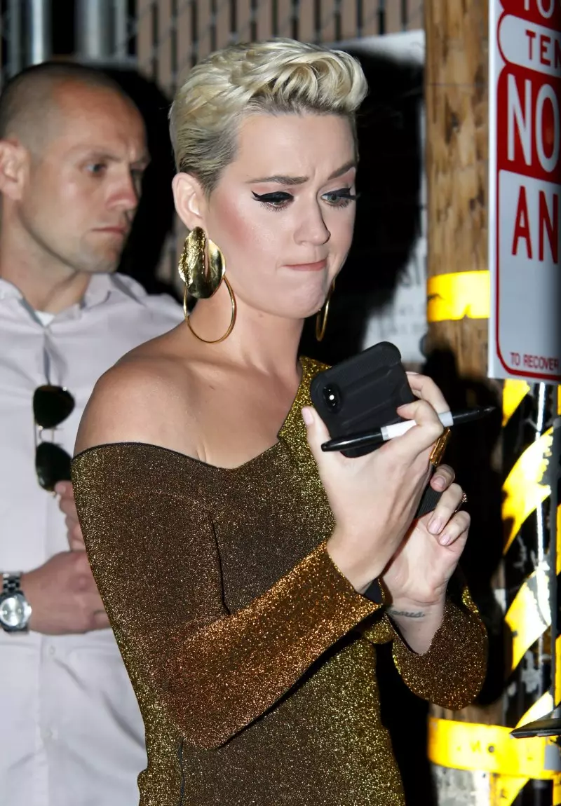 Katy Perry draacht in strakke, gouden jurk mei swarte sinnebril