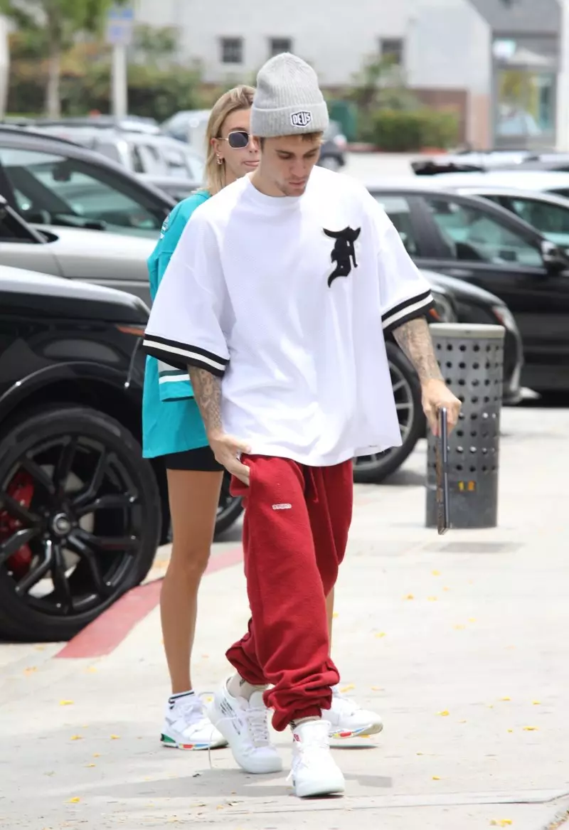 Justin Bieber veľké červené nohavice oversized biele tričko a Hailey Baldwin žraločí dres čierne šortky slnečné okuliare