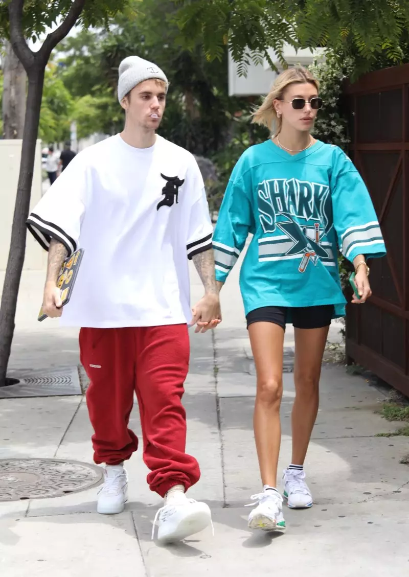 Justin Bieber veľké červené nohavice oversized biele tričko a Hailey Baldwin žraločí dres čierne šortky slnečné okuliare