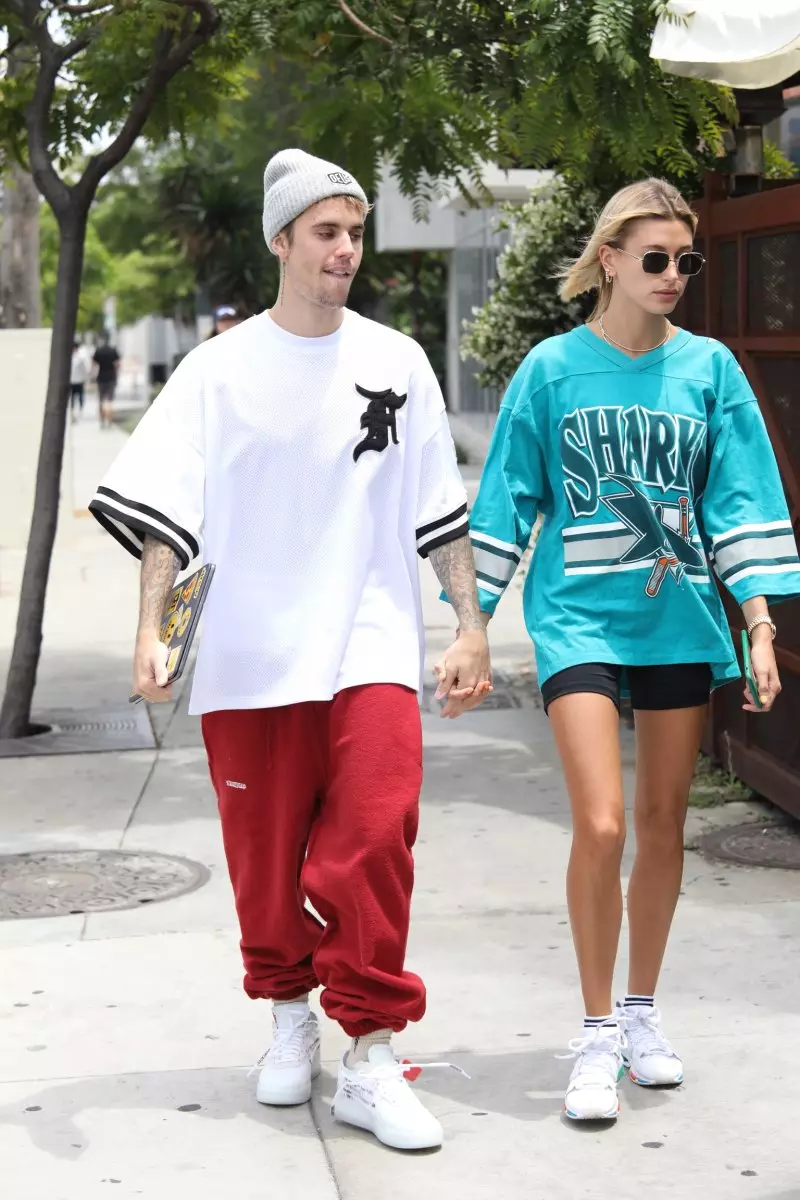 Justin Bieber veľké červené nohavice oversized biele tričko a Hailey Baldwin žraločí dres čierne šortky slnečné okuliare