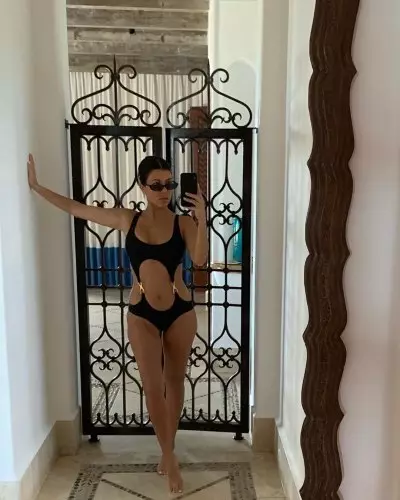 Kourtney Kardashian macht ein Spiegel-Selfi in einem schwarzen, ausgeschnittenen Badeanzug und einer Sonnenbrille