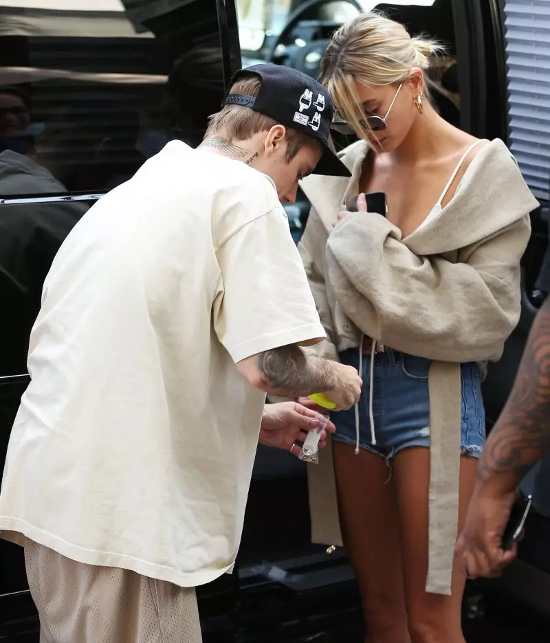 Justin Bieber porte un t-shirt beige Drew House et un short beige avec Hailey Baldwin en short en jean, un débardeur blanc et une veste beige