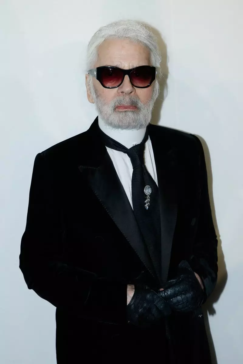 Karl Lagerfeld nosi crno odijelo, crne sunčane naočale i bijeli konjski rep