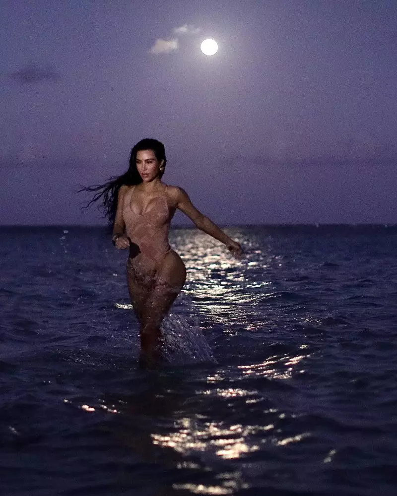 Kim Kardashian etale koub nan bikini nwa ak toutouni yon sèl pyès pou Skims Naje Photo Shoot