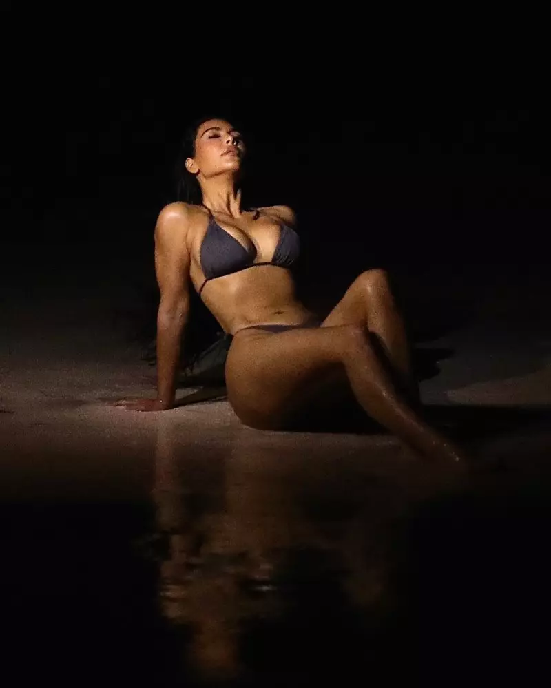 Kim Kardashian etale koub nan bikini nwa ak toutouni yon sèl pyès pou Skims Naje Photo Shoot