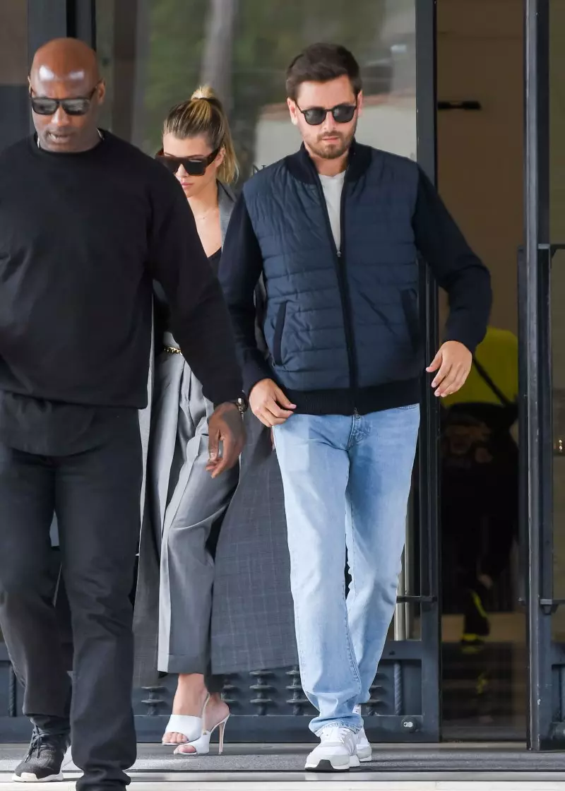 Sofia Richie traje azul gris pantalones de talle alto cinturón de cadena dorada camiseta sin mangas negra gafas de sol de cola de caballo Scott Disick chaqueta azul camiseta gris jeans azules gafas de sol