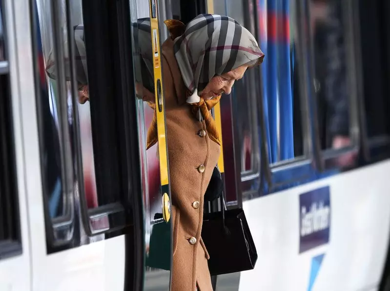 A rainha se envolve para se aquecer enquanto anda de trem público antes dos feriados