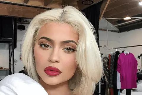 D'Kylie Jenner poséiert fir e Selfie mat blonden Hoer a roude Lippenstift.