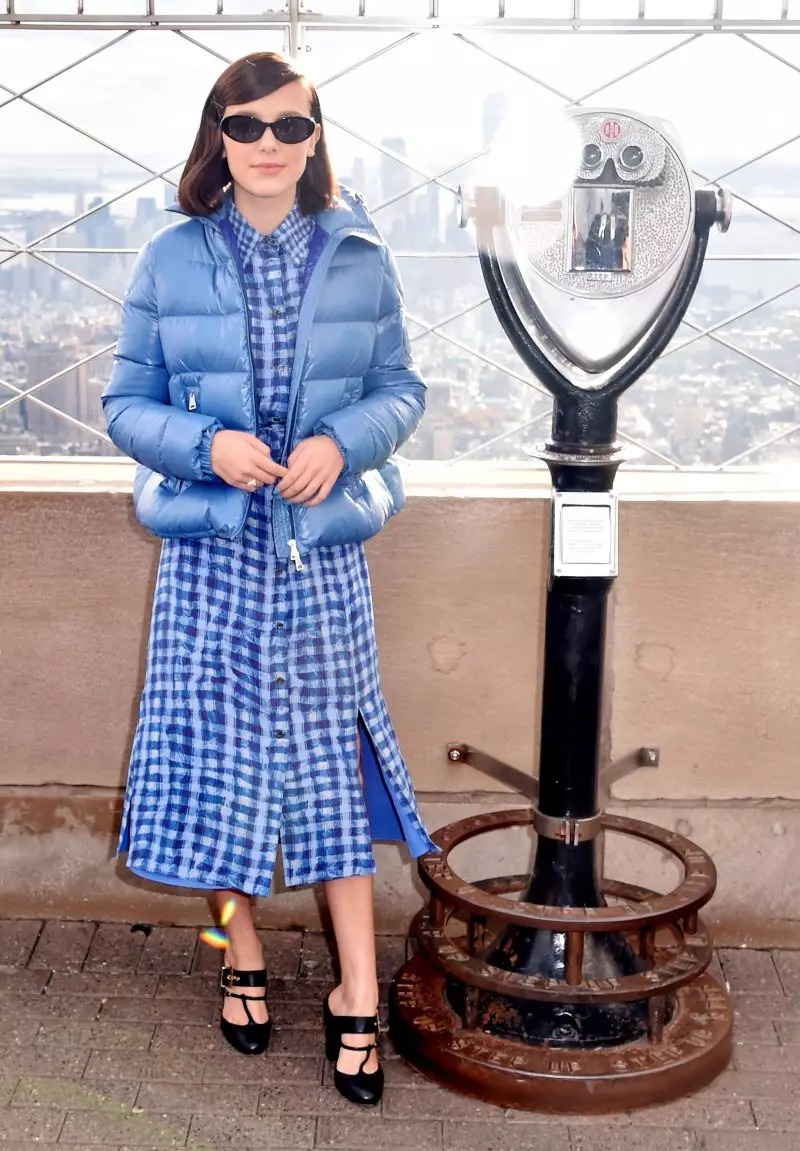 Millie Bobby Brown na sobě Altuzarra, boty od Chloe Gosselin Blue Puffy Coat a kostkované šaty