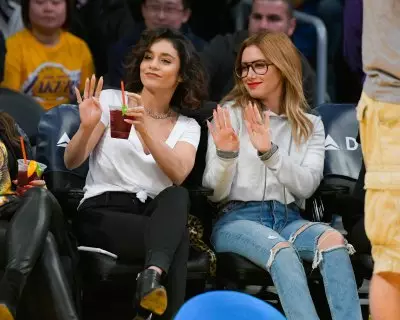 Ashley Tisdale con gafas y vaqueros con Vanessa Hudgens con vaqueros y una camiseta blanca en un partido de baloncesto