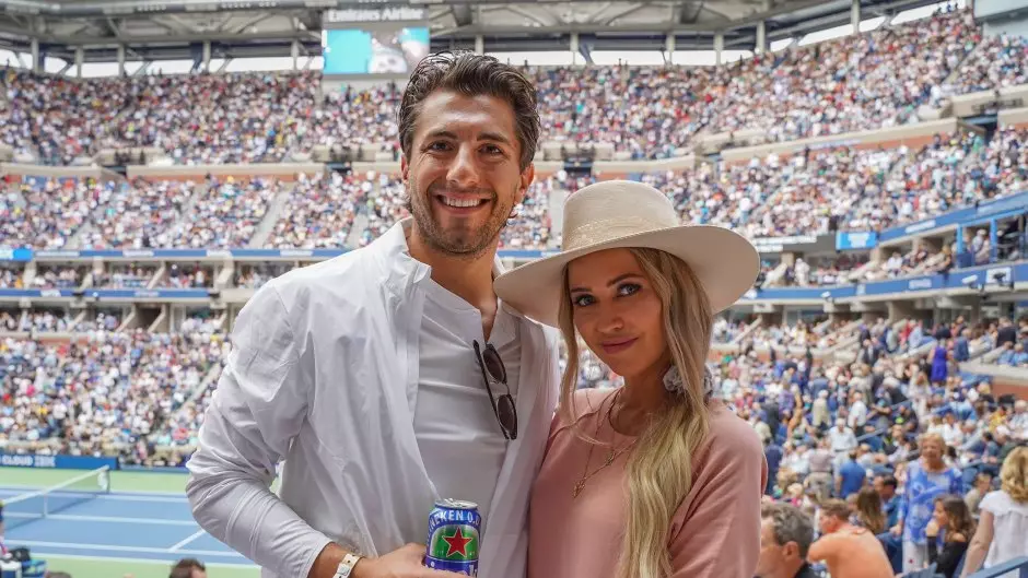 Kaitlyn Bristowe amb un barret blanc i un vestit rosa amb Jason Tartick amb una camisa blanca a l'Open dels EUA